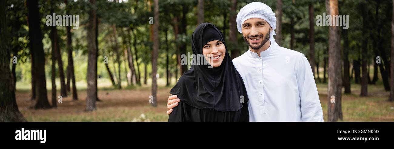 Arabian man hugging wife in hijab in park, banner Stock Photo - Alamy