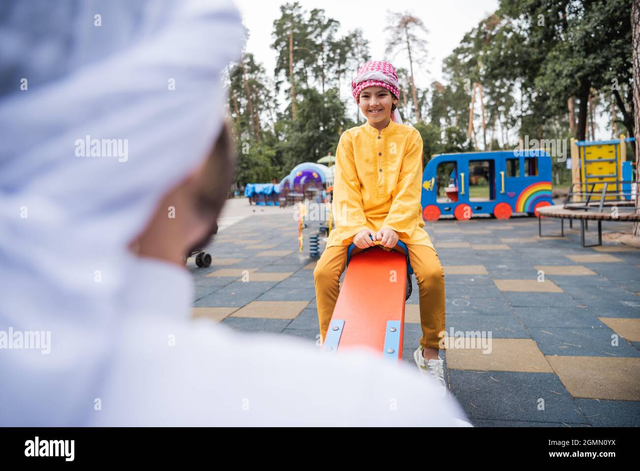 Smiling son spending time with muslim father on playground outdoors ...