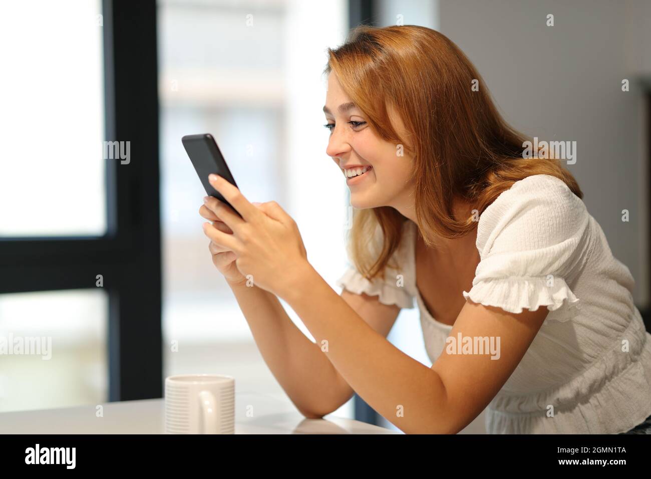 Happy woman reading text on smart phone at home Stock Photo - Alamy