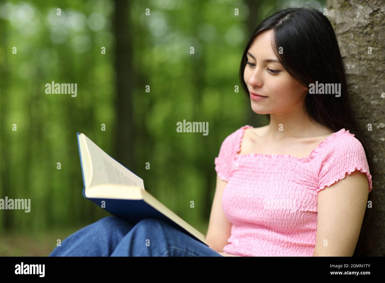 Asian woman reading paper book sitting in a park Stock Photo - Alamy
