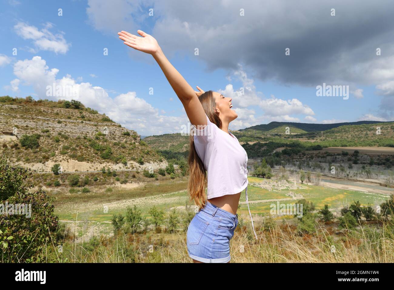 Euphoric woman outstretching arms in the mountain celebrating vacation ...