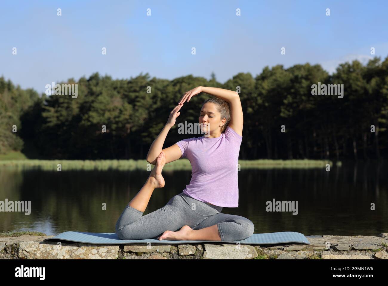 Full body portrait of a woman doing yoga advanced pose in a lake on ...