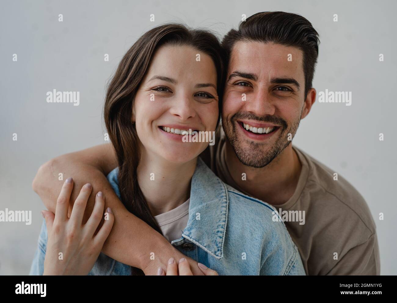 Portrait od happy young couple hugging and looking at camera, on white ...
