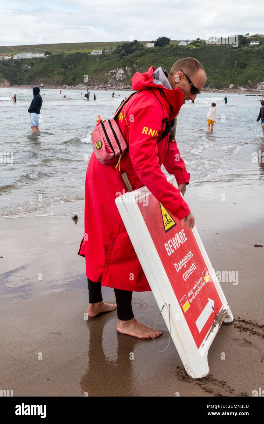 A RNLI lifeguard moves a warning sign along Bantham Beach, Devon Stock ... A RNLI lifeguard moves a warning sign along Bantham Beach, Devon Stock ...