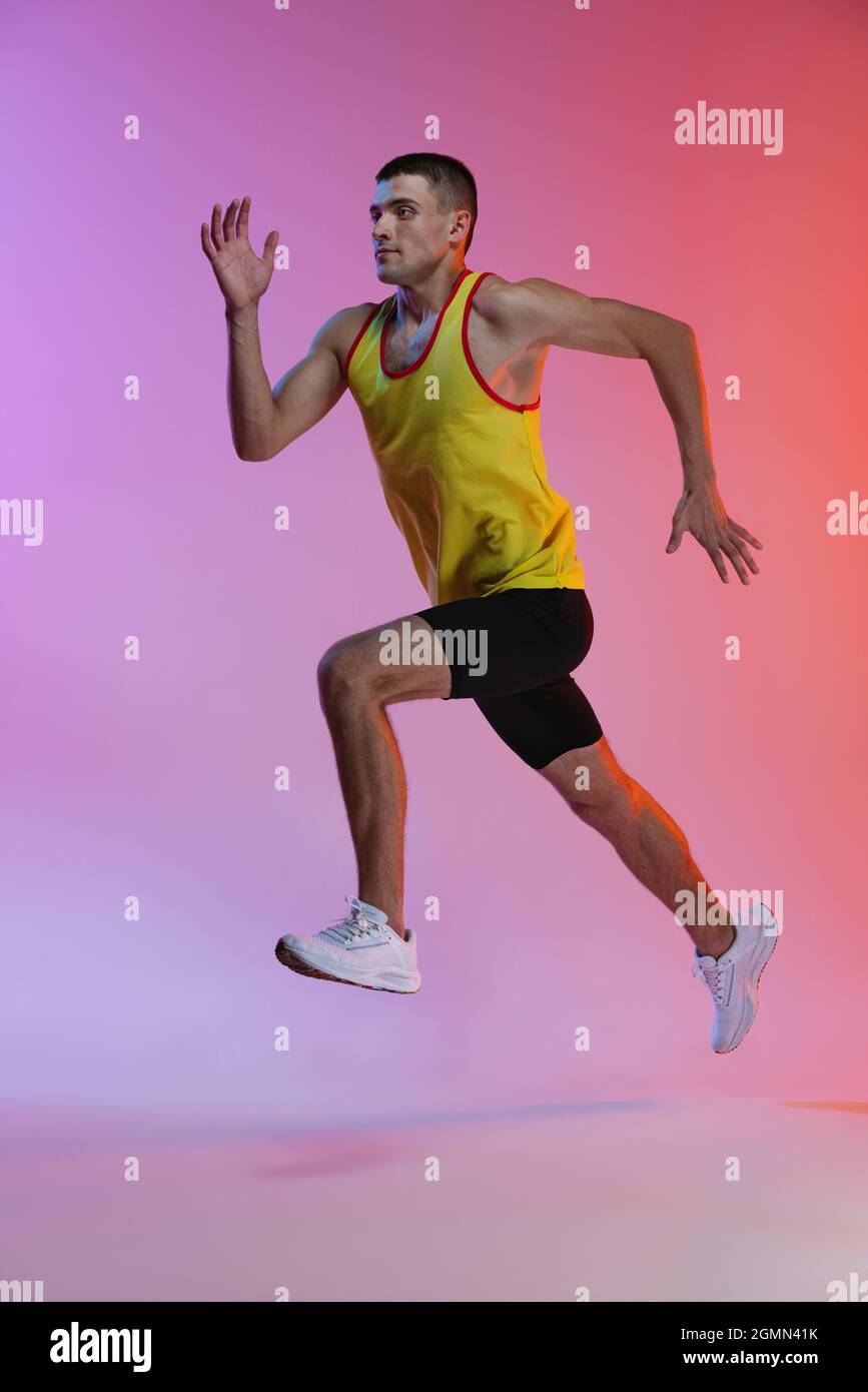 Portrait in motion of young male athlete running isolated over gradient ...