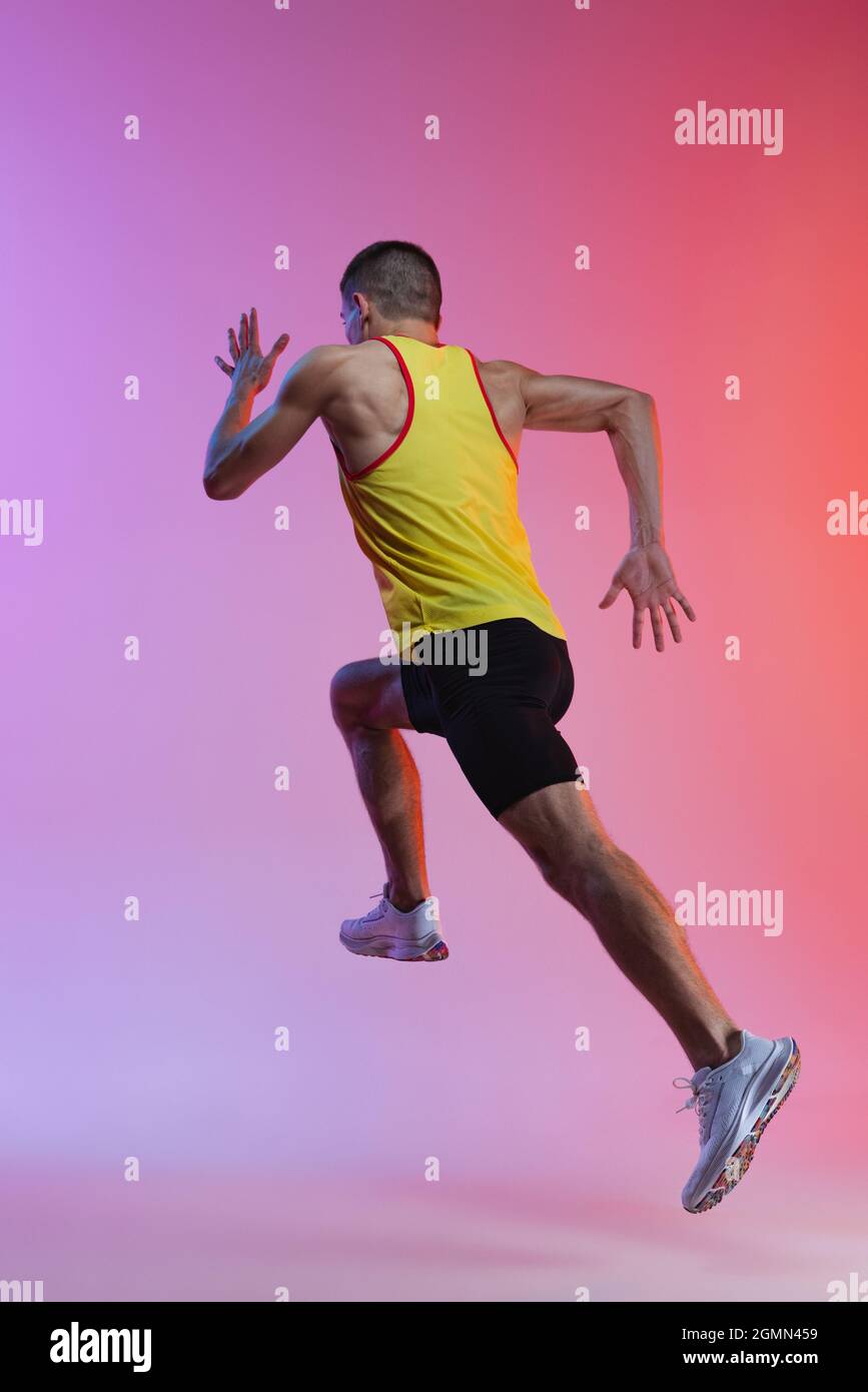 Back side view portrait of young male athlete running isolated over ...