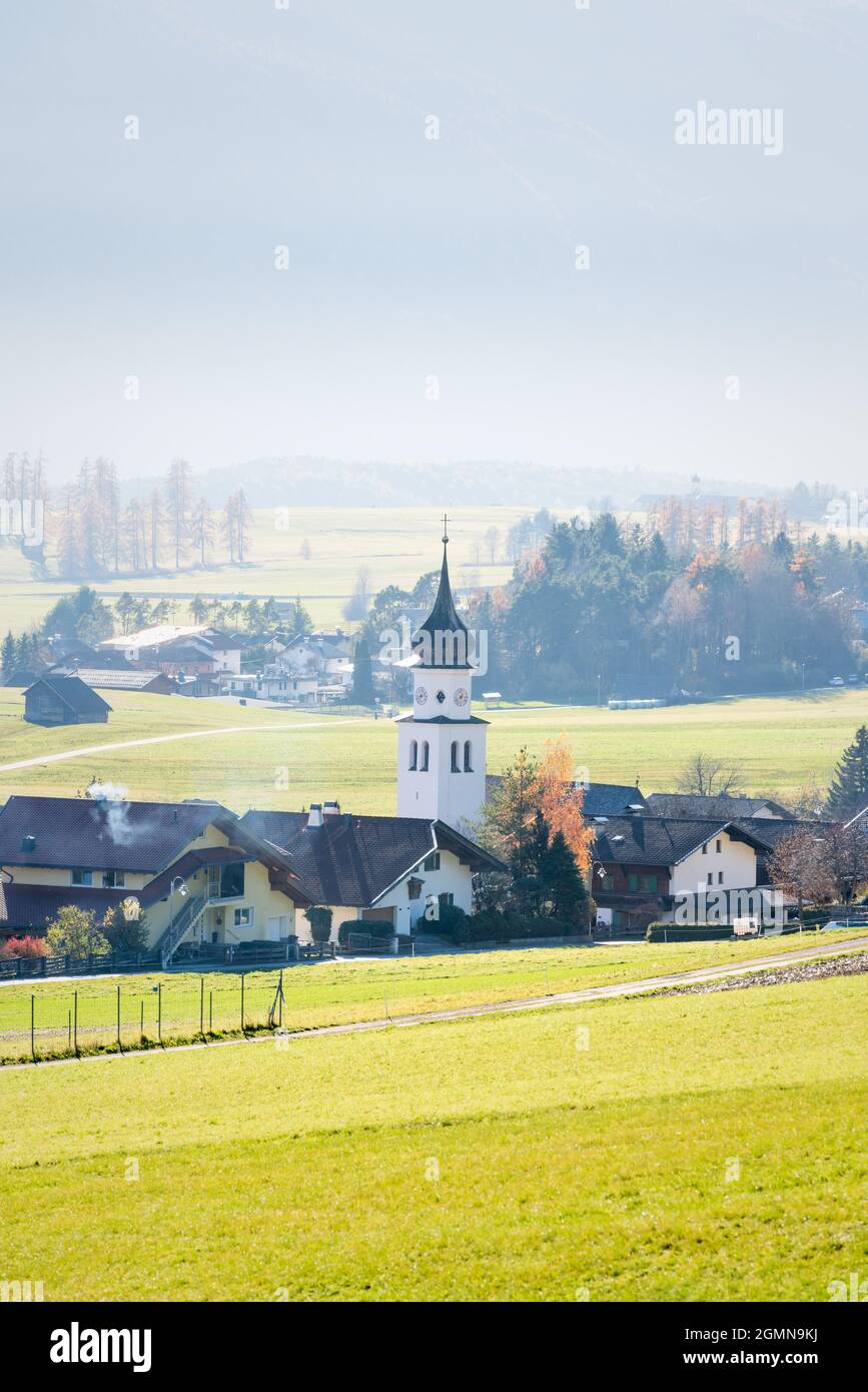 Sunny Austrian mountain village with misty valley background during ...