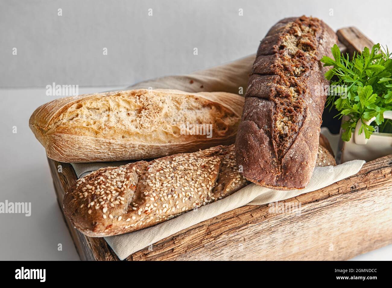 Assortment of bread in a wooden old rustic box. Various types of greens ...