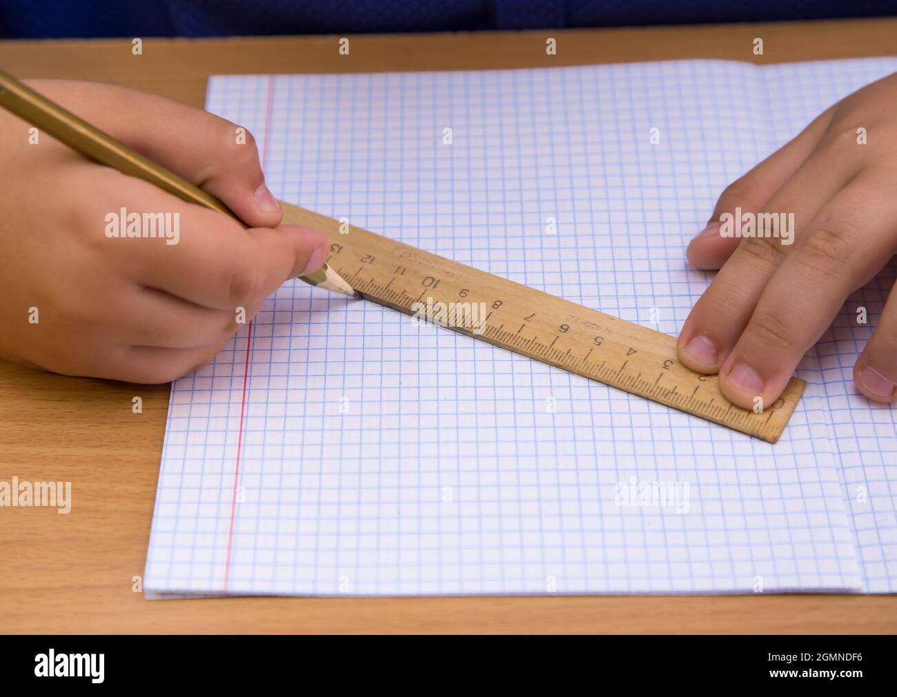 The student draws a straight line with a pencil along the ruler. A ...