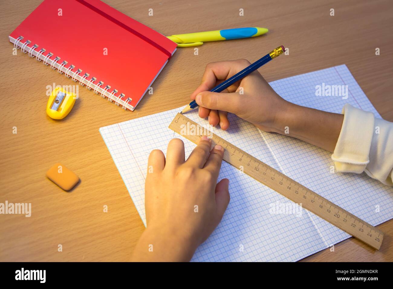 A student in a notebook draws a figure with a pencil along a ruler. A ...