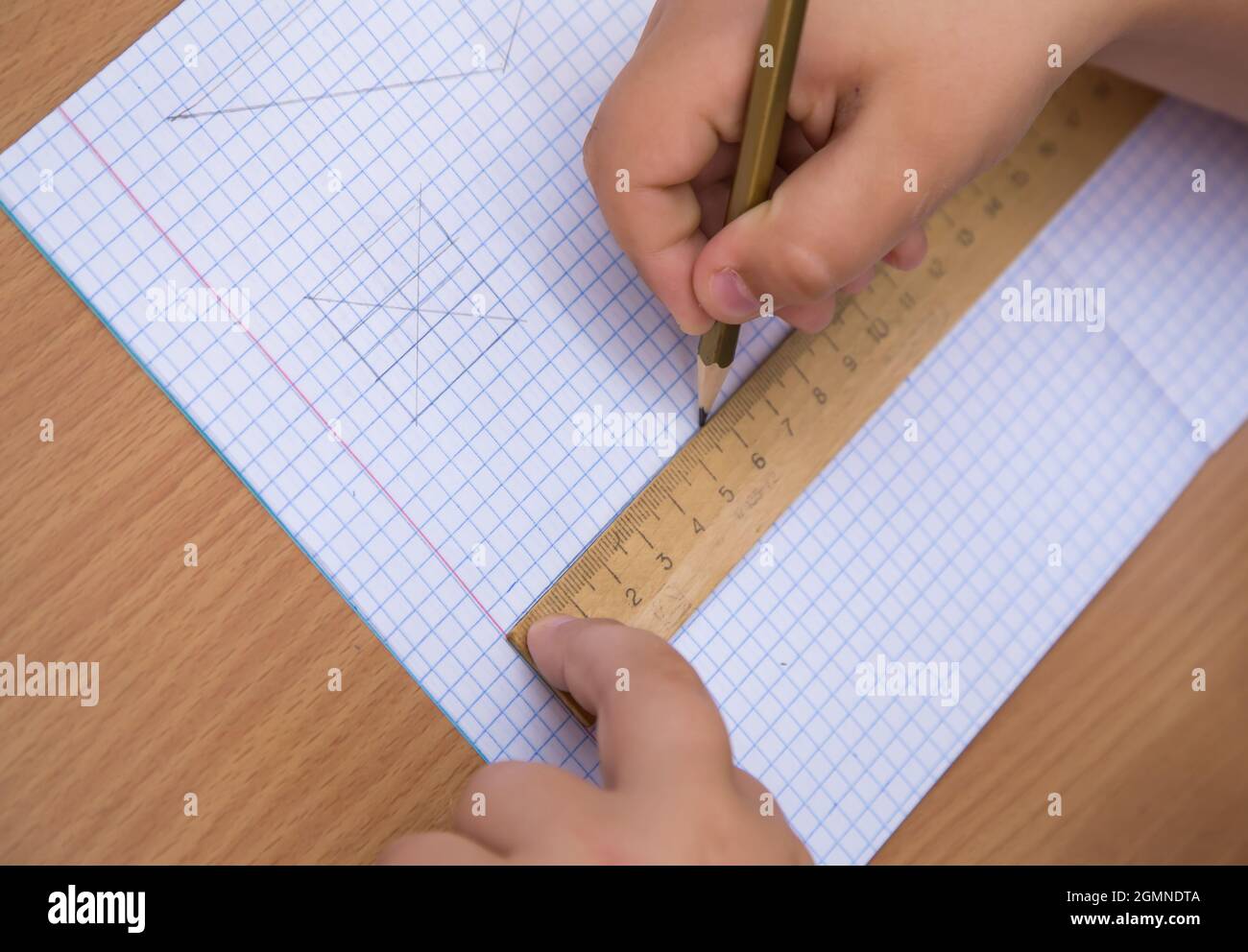 The student draws a straight line in a notebook with a pencil along a ...