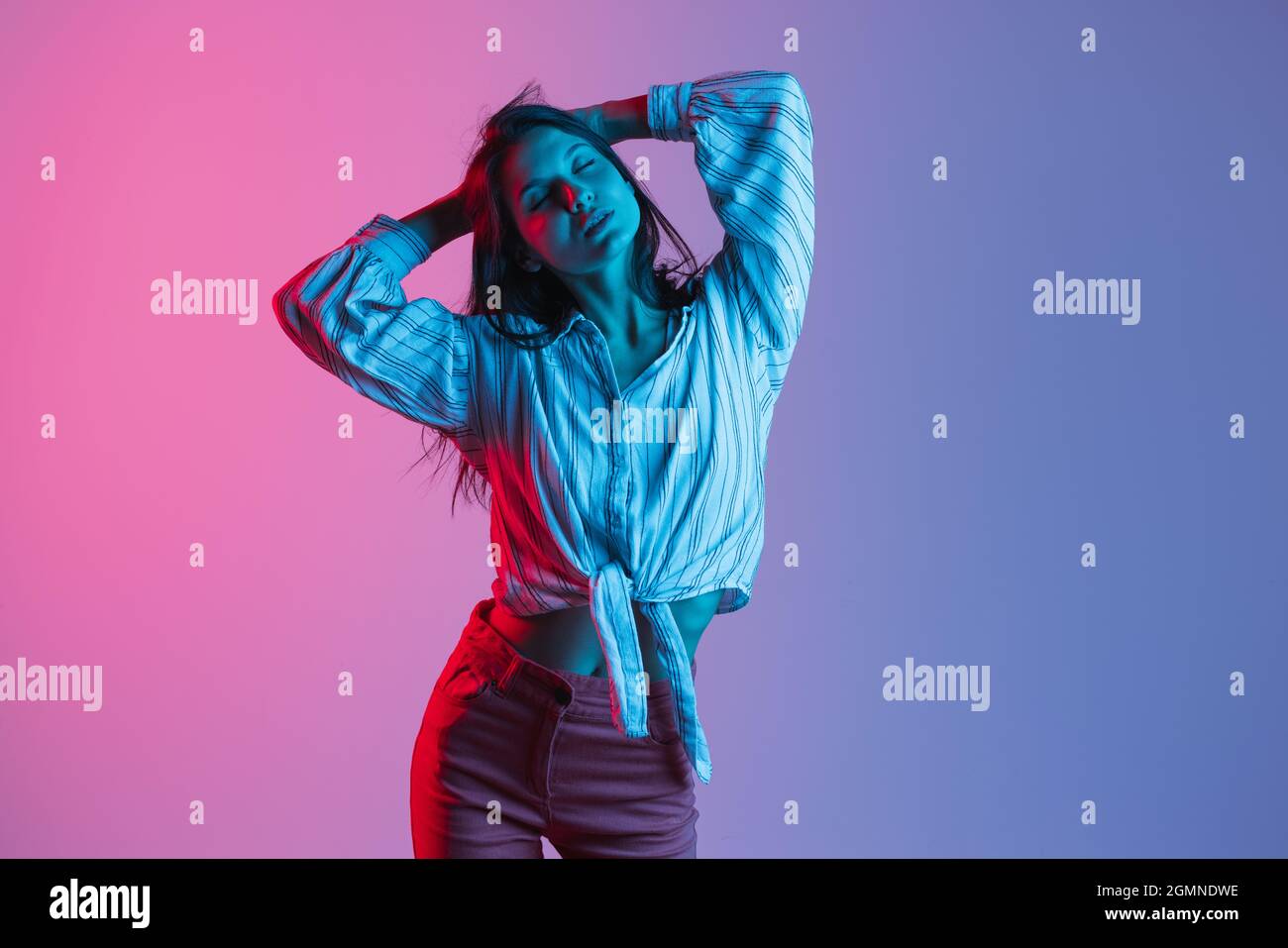 Beautiful young girl dancing isolated over gradient pink purple ...