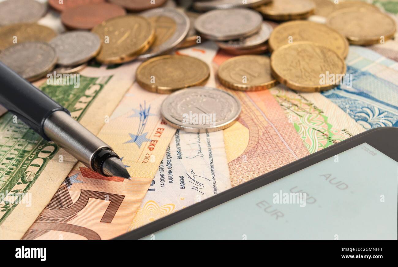 smartphone and ink pen lying on a background of banknotes and coins of ...