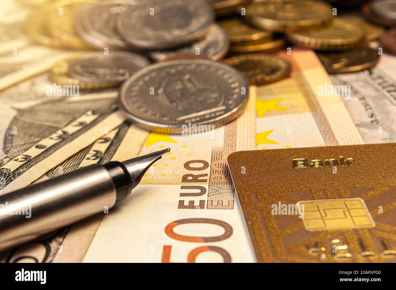 credit card and ink pen lying on a background of banknotes and coins of ...