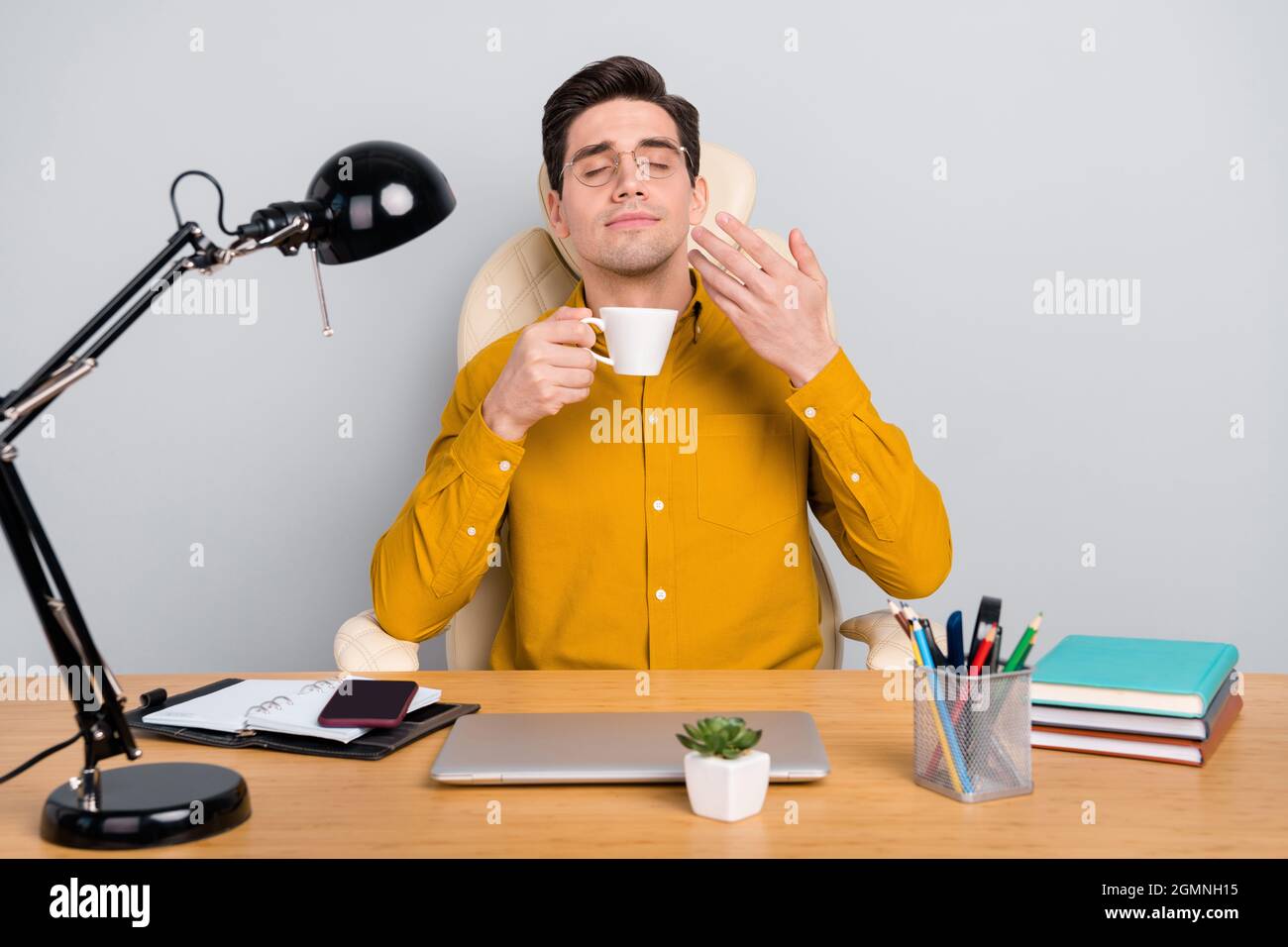 Portrait of attractive man sitting in chair drinking espresso smelling ...