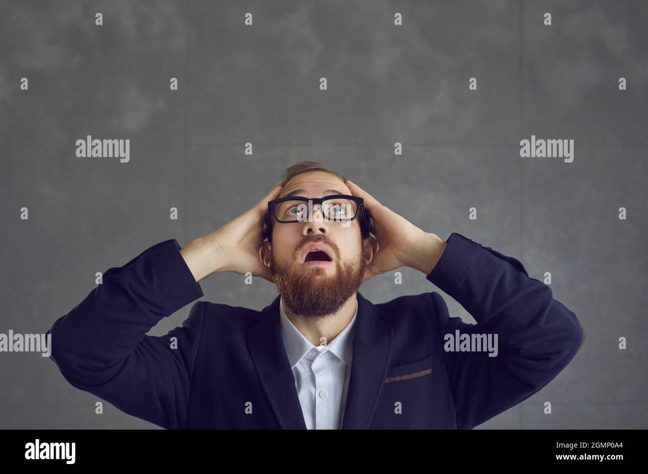 Businessman in suit and glasses looking up with expression of surprise ...