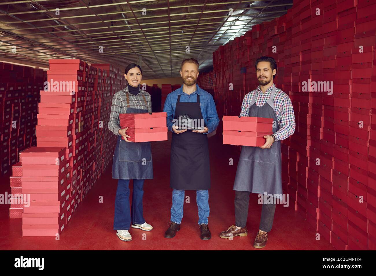 Team of happy shoe factory workers standing in warehouse and showing ...