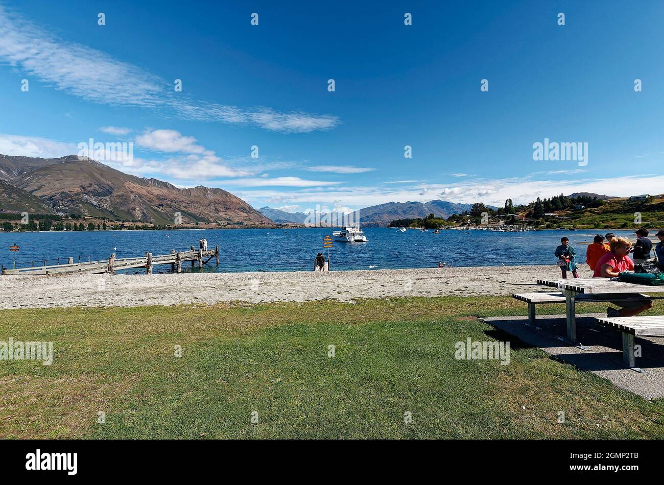 Lake Wanaka; scenic, blue water, hills, sand beach, people, boats, pier ...