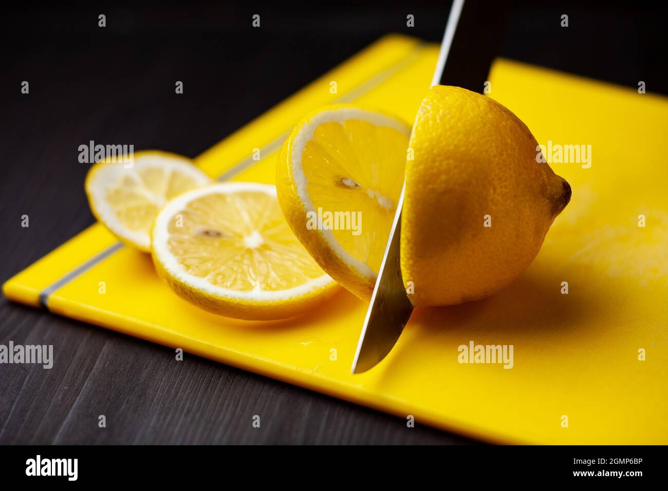 Cutting lemon in pieces, yellow cutting board on dark background Stock ...