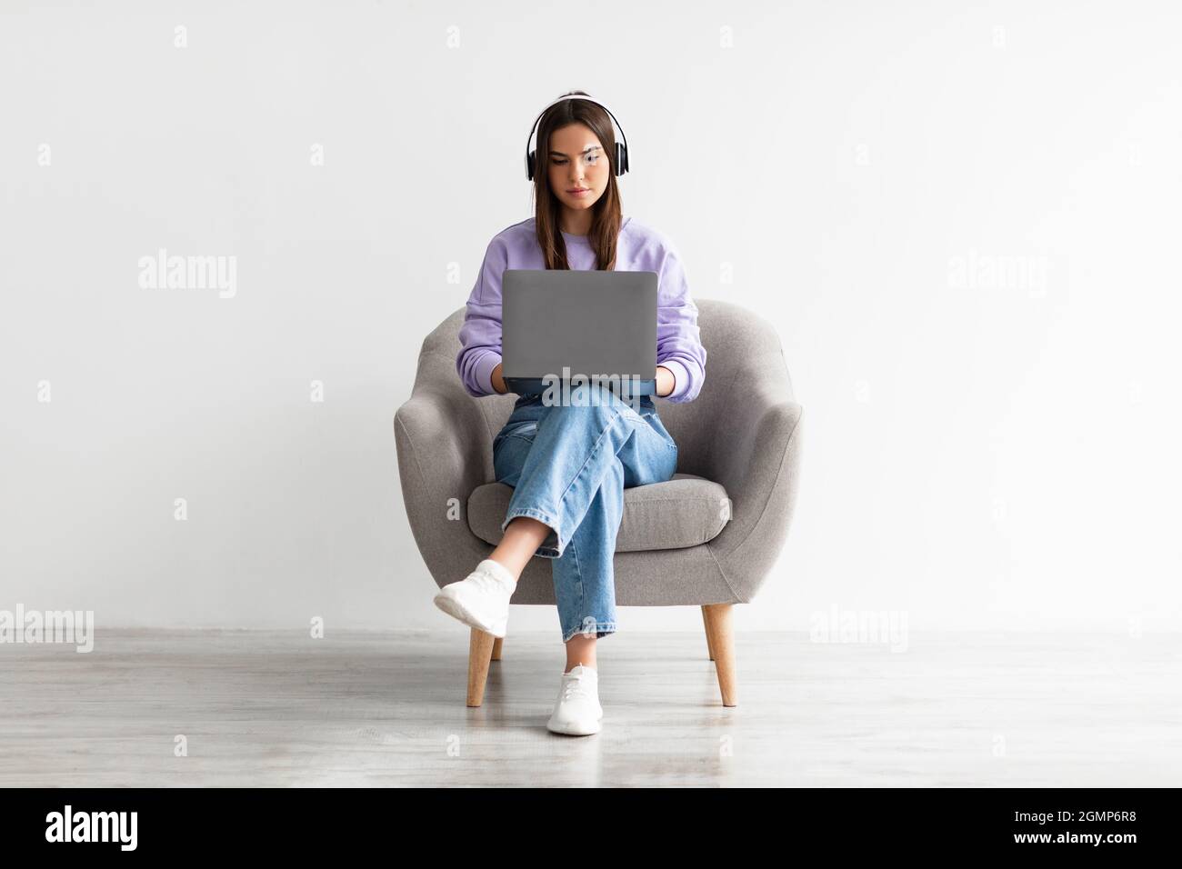 Young Caucasian woman having video call, using laptop computer, sitting ...
