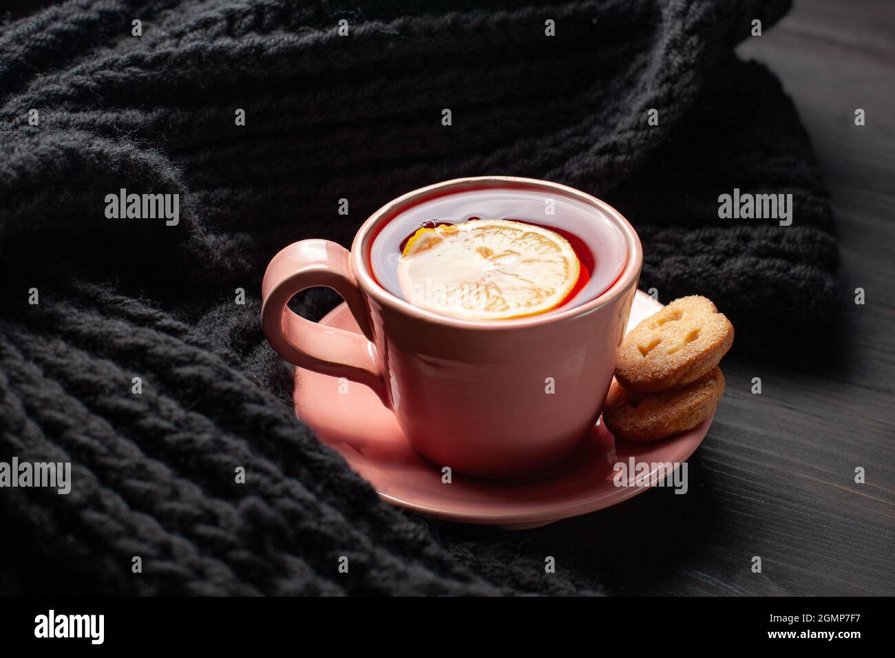 Mug of tea and knitted scarf on black wooden background Stock Photo - Alamy