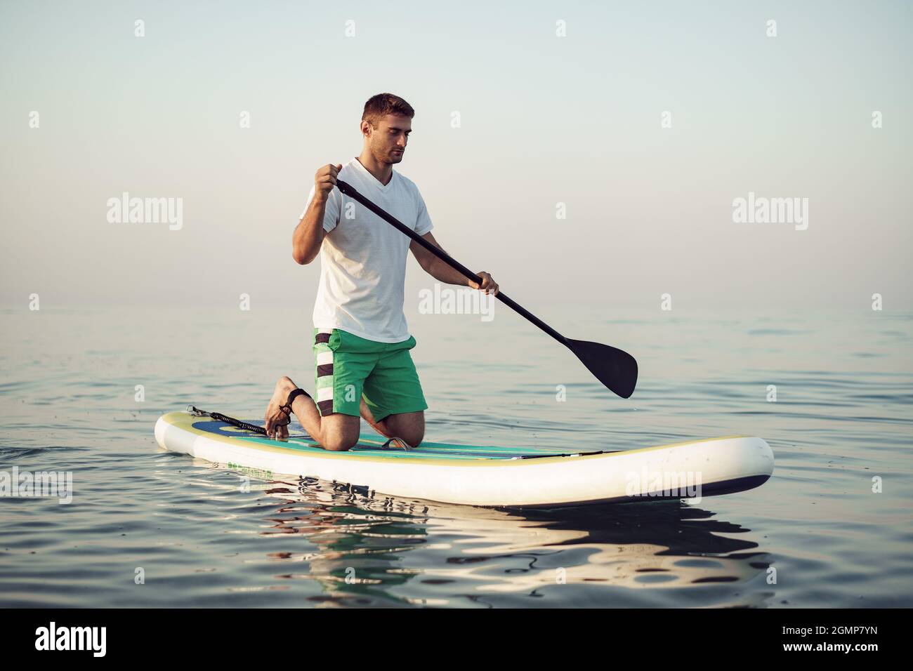 Young man in t-shirt and shorts floating on SUP board Stock Photo - Alamy
