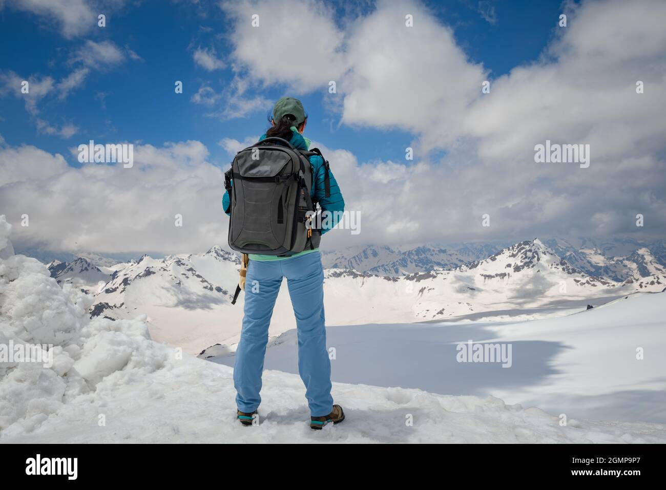 Hiker woman standing up achieving the top. View at the snowy mountains ...