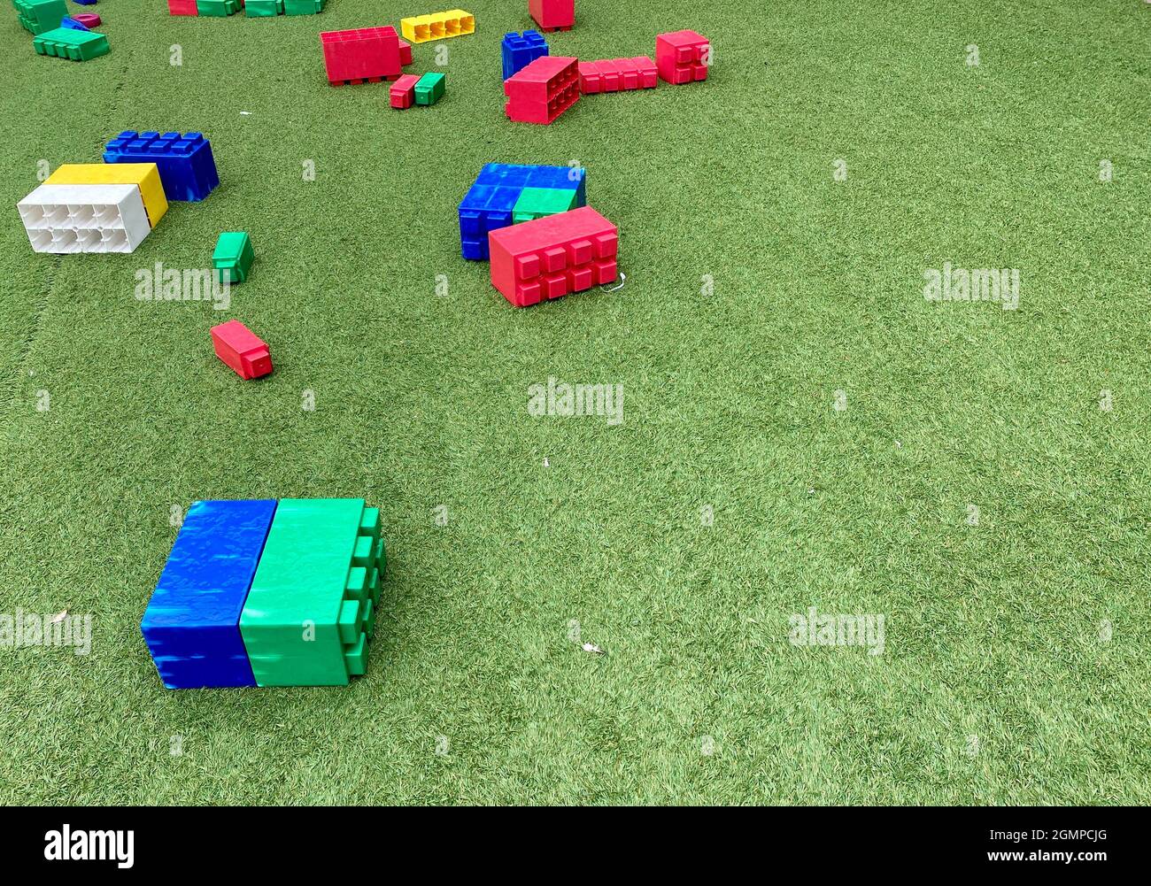 Plastic construction blocks strewn on an artificial turf play area ...