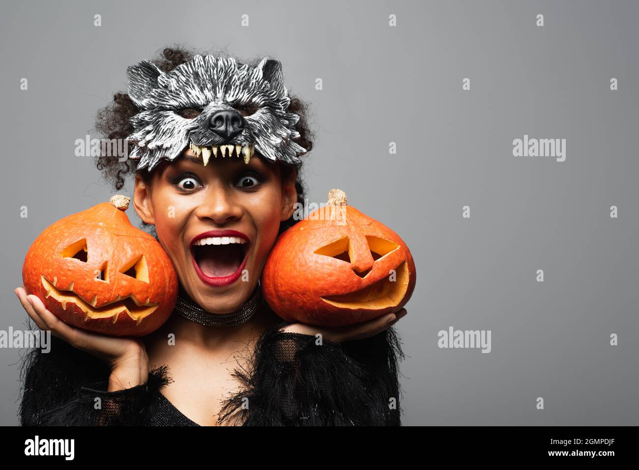 astonished african american woman in wolf halloween mask holding carved ...