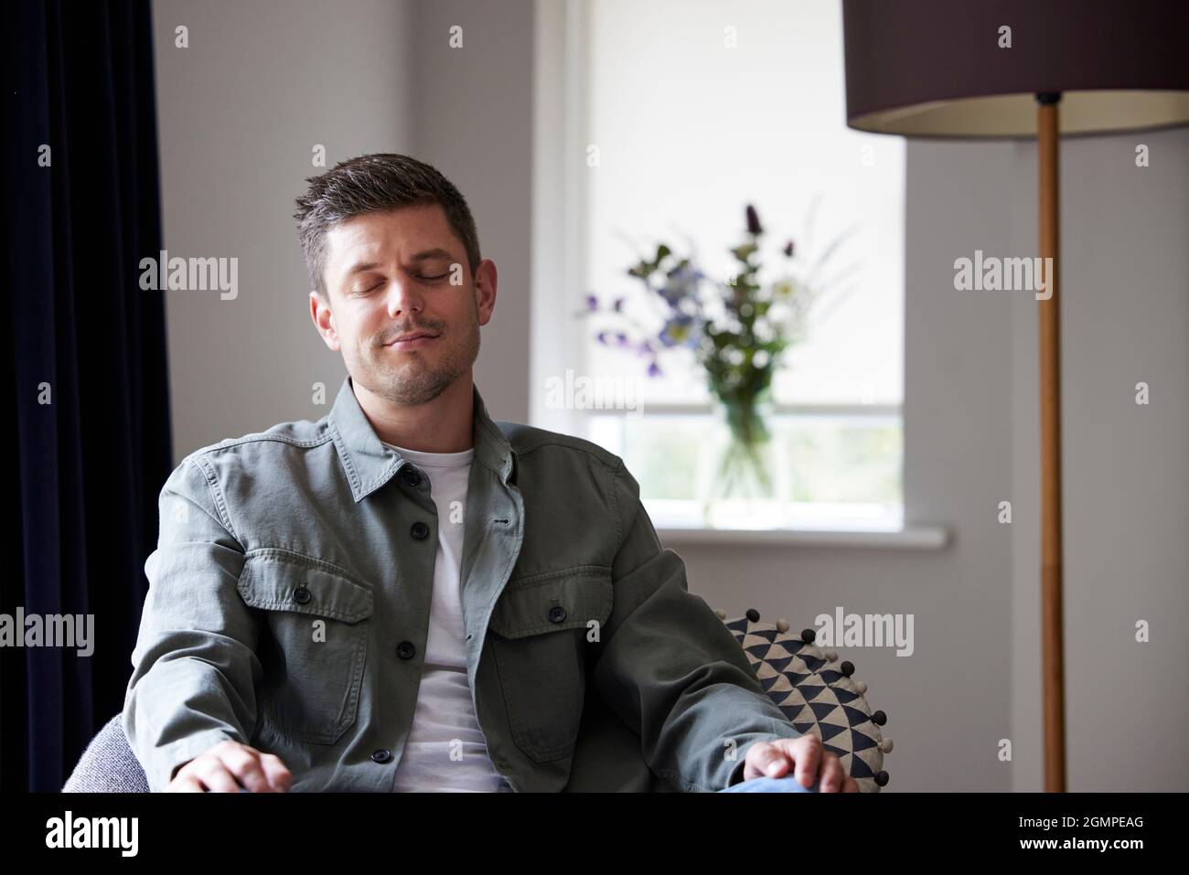 Peaceful Man Meditating Sitting In Chair At Home Stock Photo - Alamy