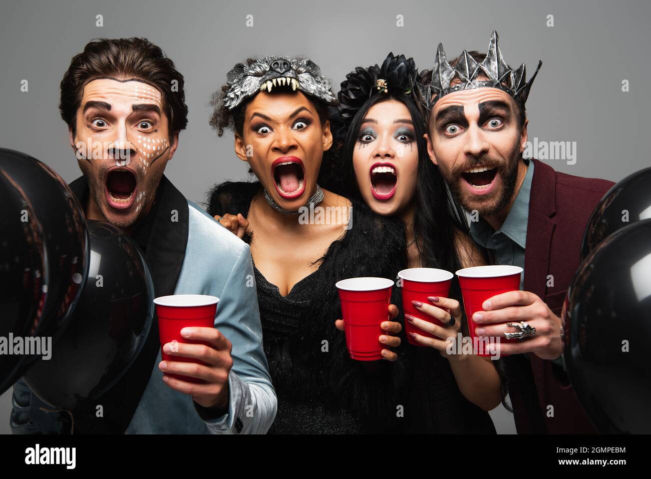 spooky multiethnic friends with plastic cups screaming and growling at ...