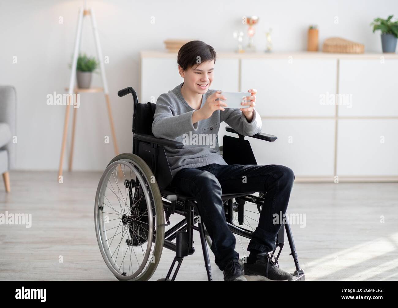 Positive disabled teenager in wheelchair having video call on ...