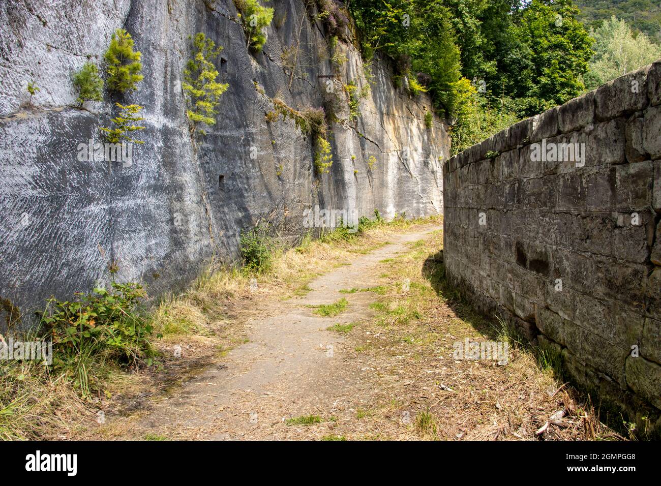 An empty footpath between a rock and a stone wall Stock Photo - Alamy
