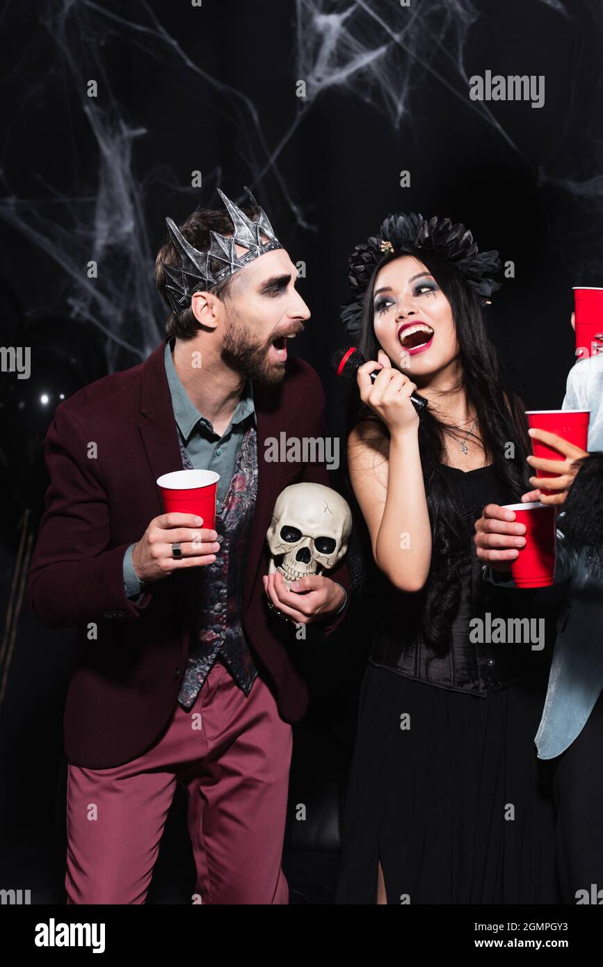 asian woman in vampire halloween costume singing karaoke with man in ...