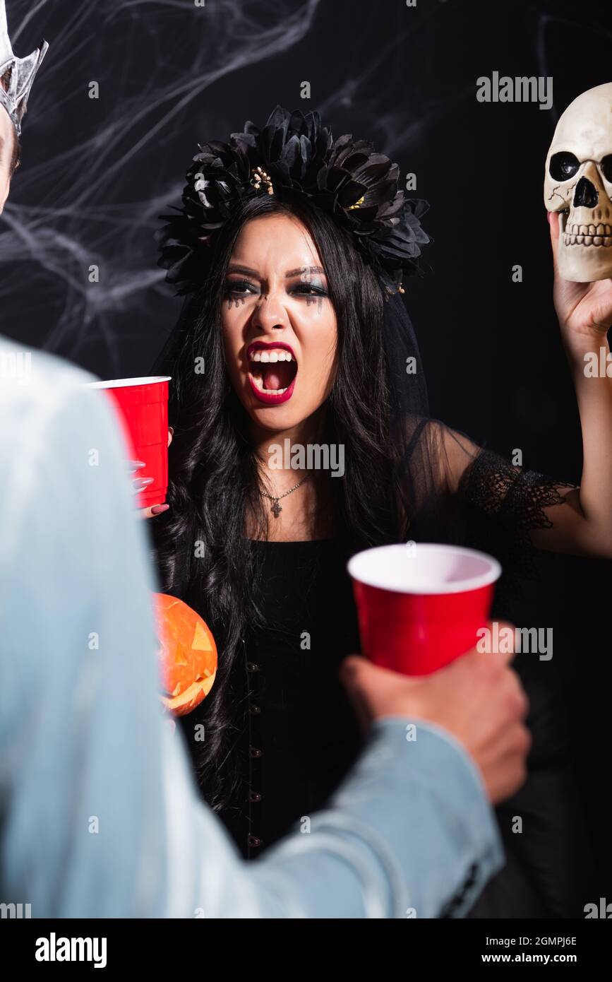 asian woman in vampire costume growling while frightening blurred man ...