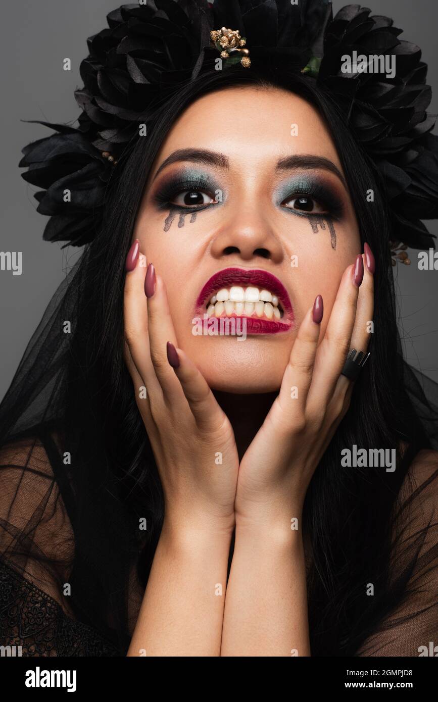 asian woman with vampire halloween makeup touching face and grinning ...