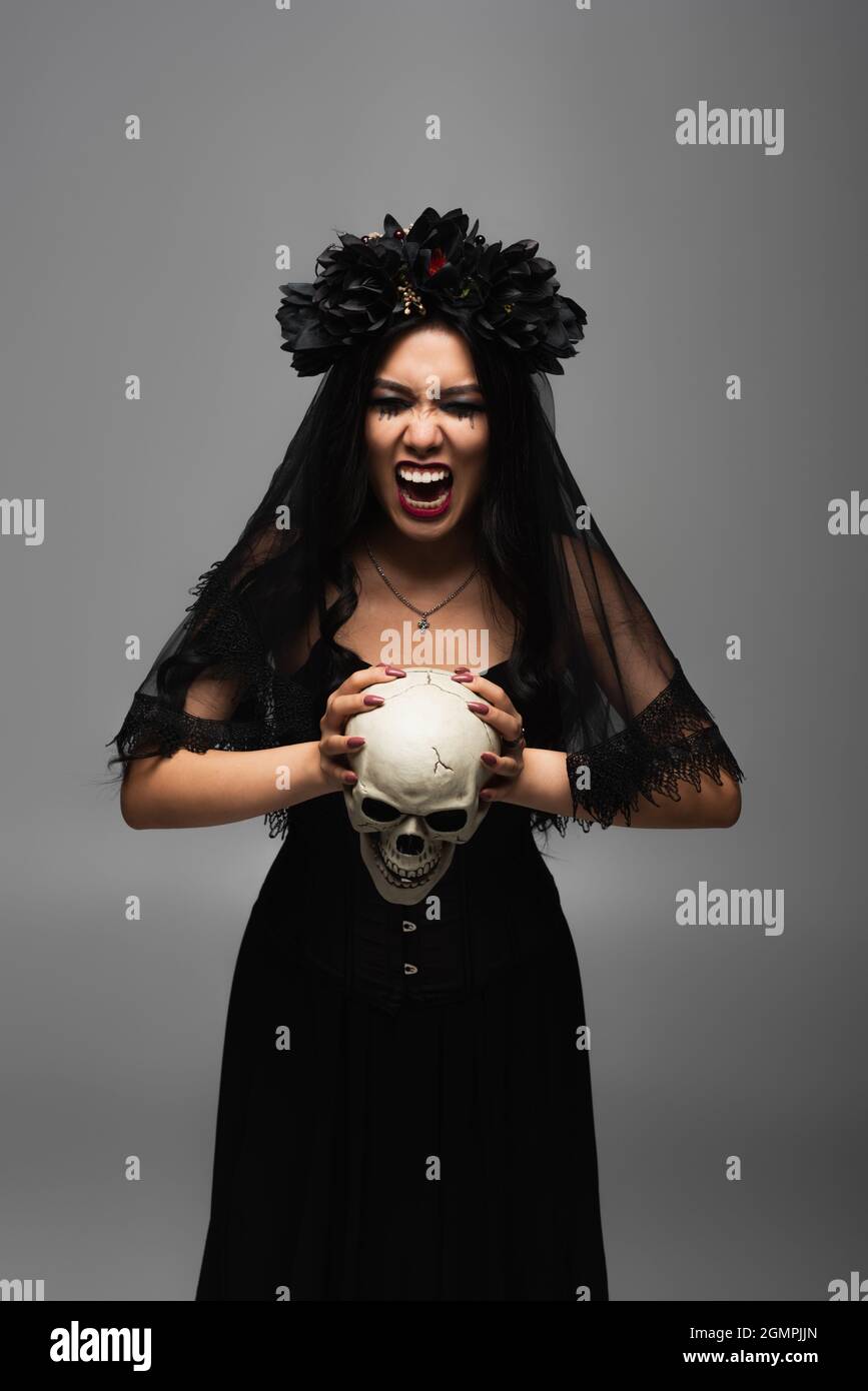 growling asian woman in vampire halloween costume holding spooky skull ...