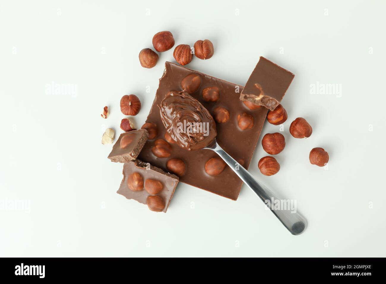 Spoon with chocolate paste and chocolate with nuts on white background ...