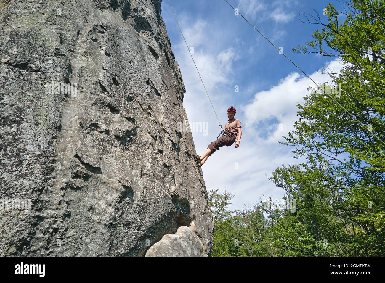 Strong male climber climbing steep wall of rocky mountain. Sportsman ...