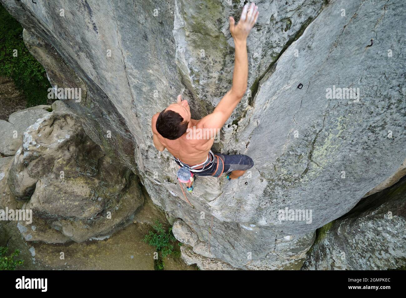 Determined climber clambering up steep wall of rocky mountain ...