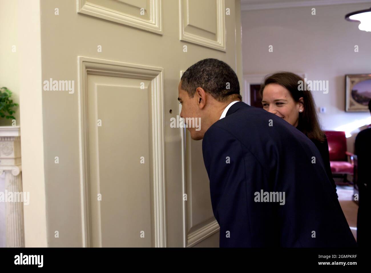 President Barack Obama looks through the Oval Office door peephole as ...