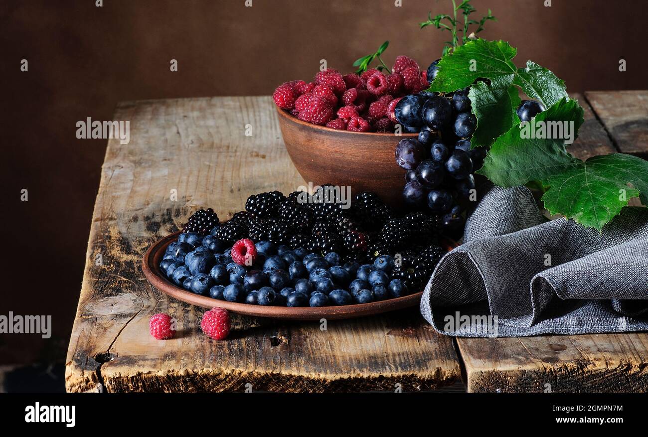 Ripe raspberries, blackberries, blueberries, grapes on a vintage wooden ...