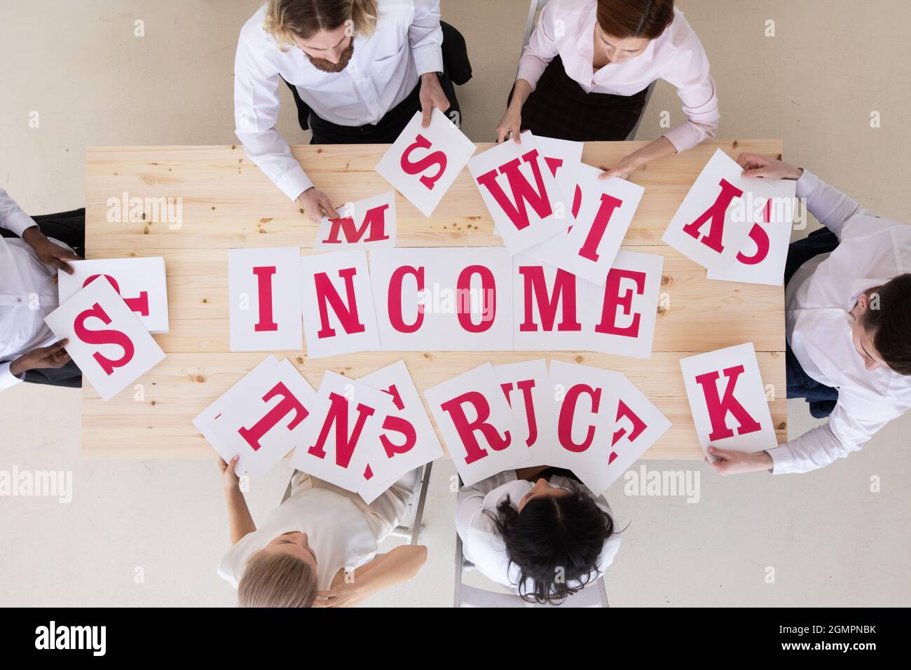 Multi-ethnic group of diverse business people putting letters INCOME ...