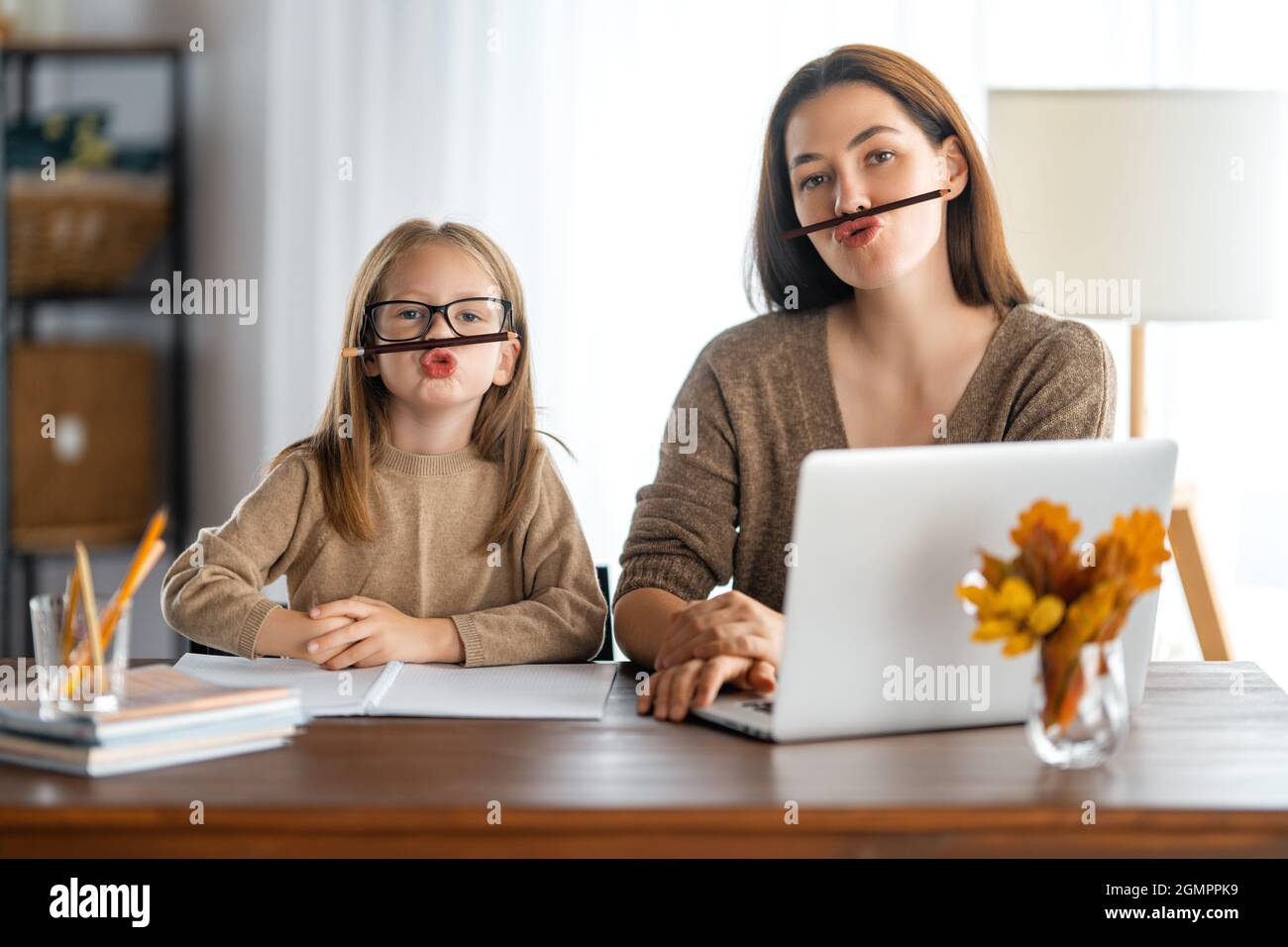 Back to school. Happy child and adult are sitting at desk. Girl doing ...