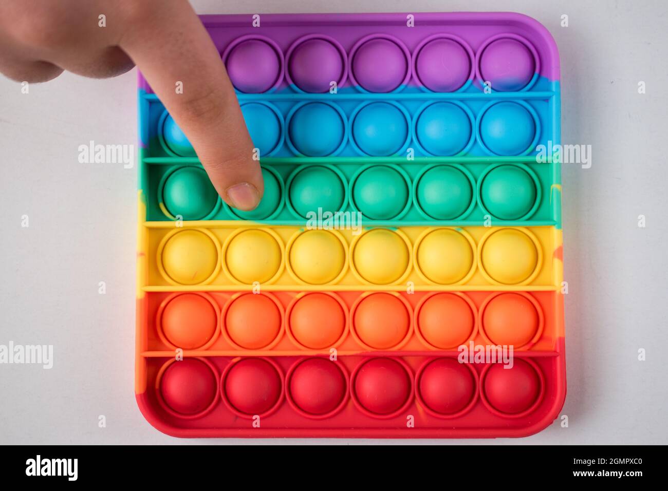 Finger pushing a point of a colorfull kids toy on a white table Stock ...