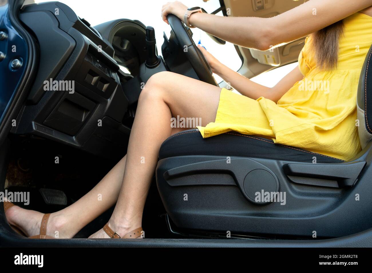 Close up of young woman driver legs in yellow summer dress sitting ...