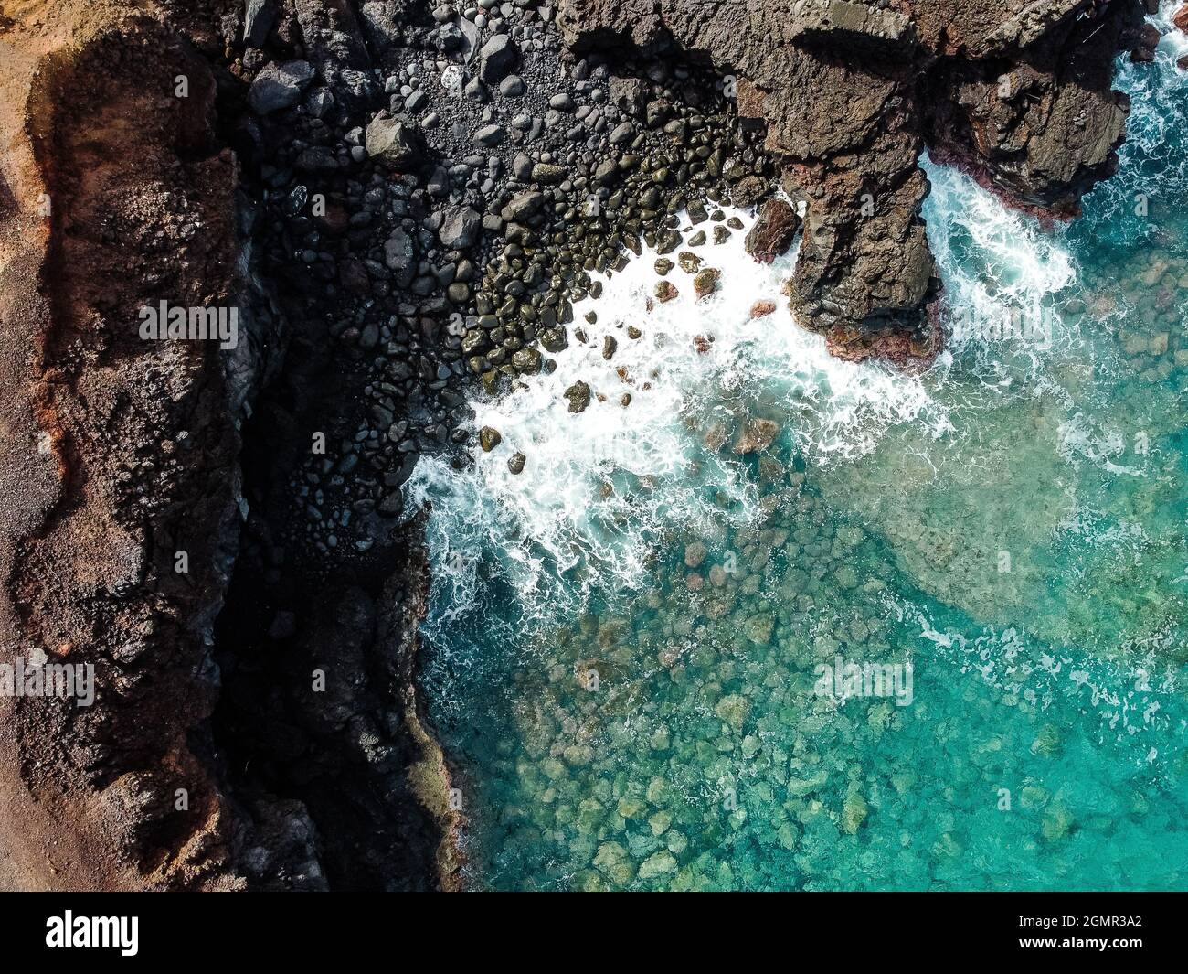 Aerial top view of rocks and sea waves in a volcanic landscape with ...