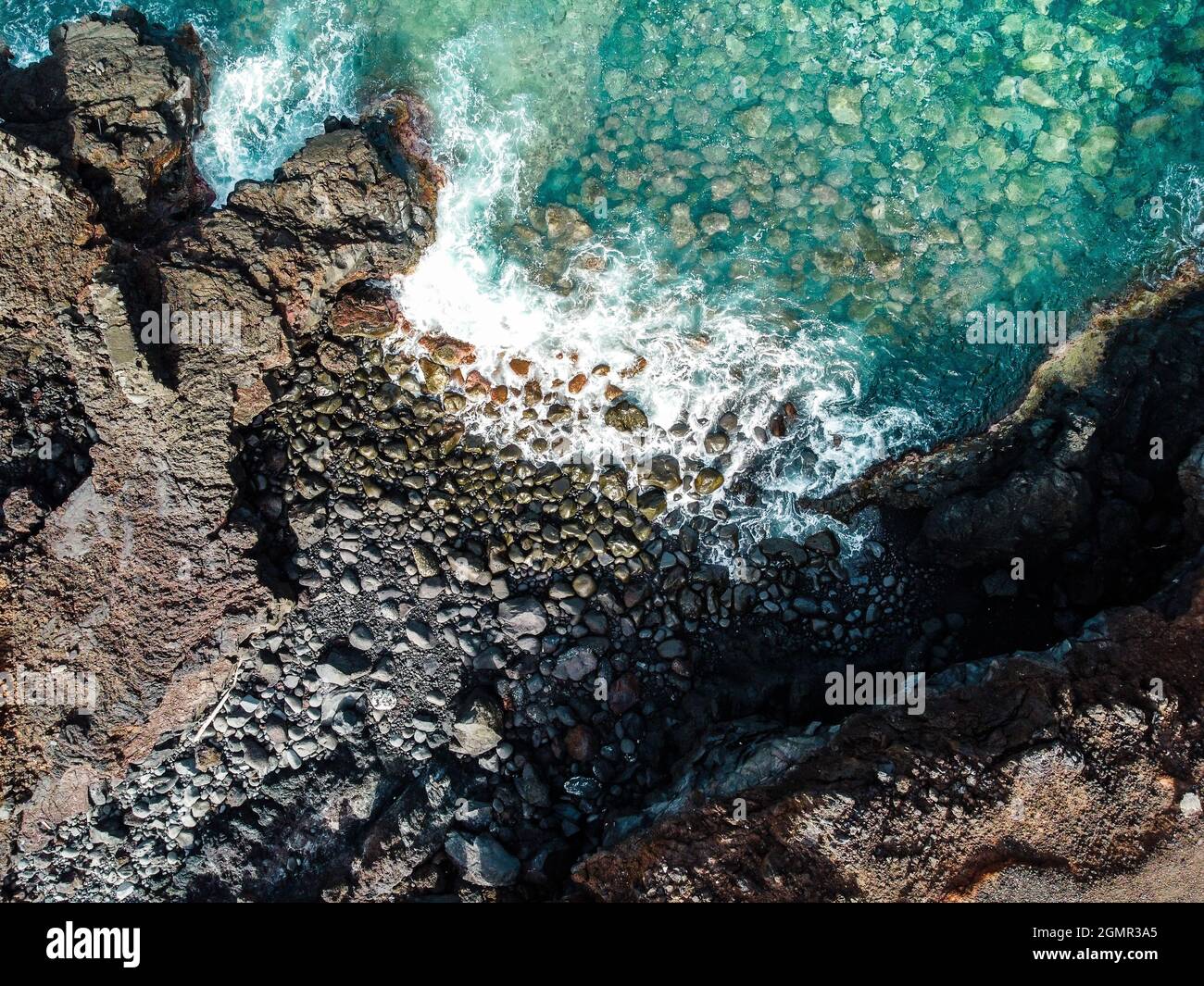 Aerial top view of rocks and sea waves in a volcanic landscape with ...