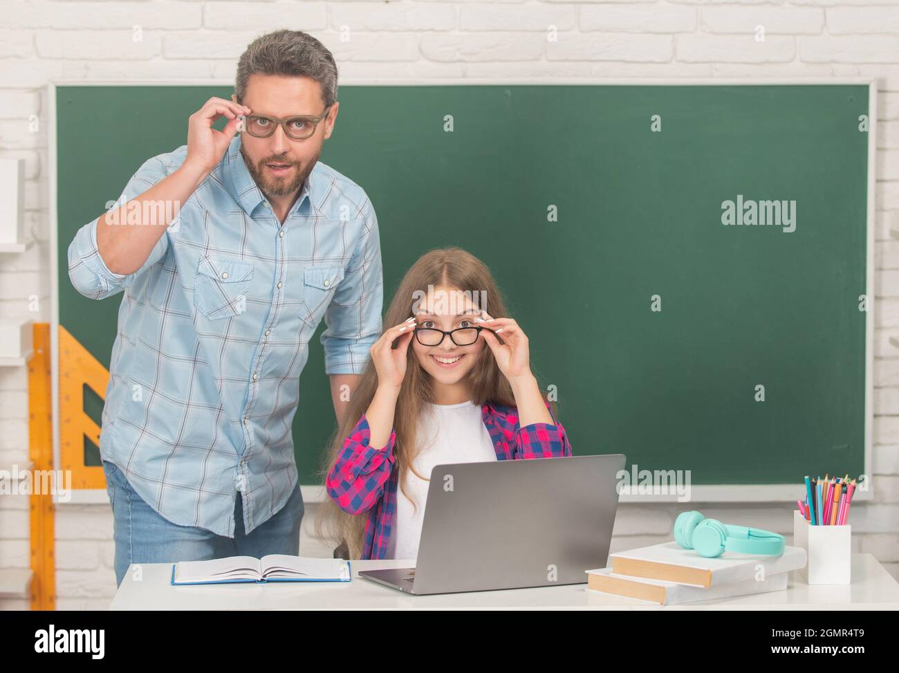 amazed kid and dad sitting in classroom with computer at blackboard, e ...