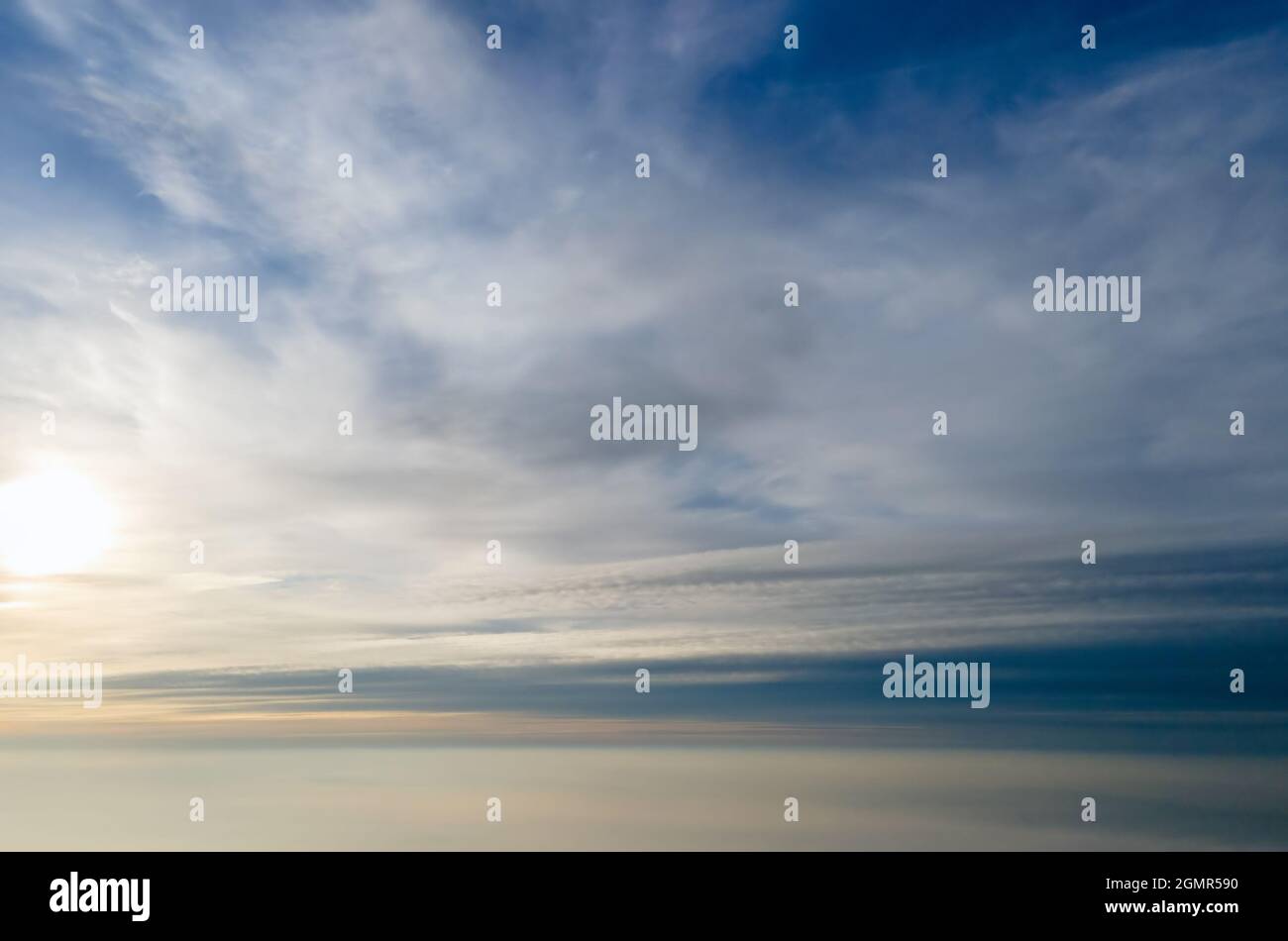 Aerial view of bright yellow sunset over white dense clouds with blue ...